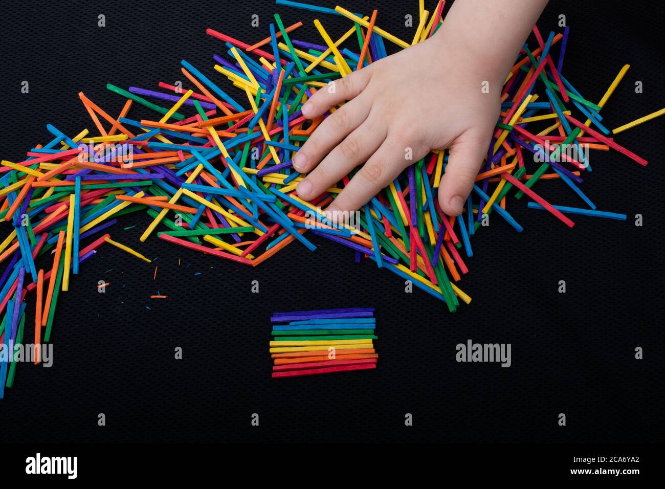 Kid playing with coloured wooden sticks for creativity on white ...