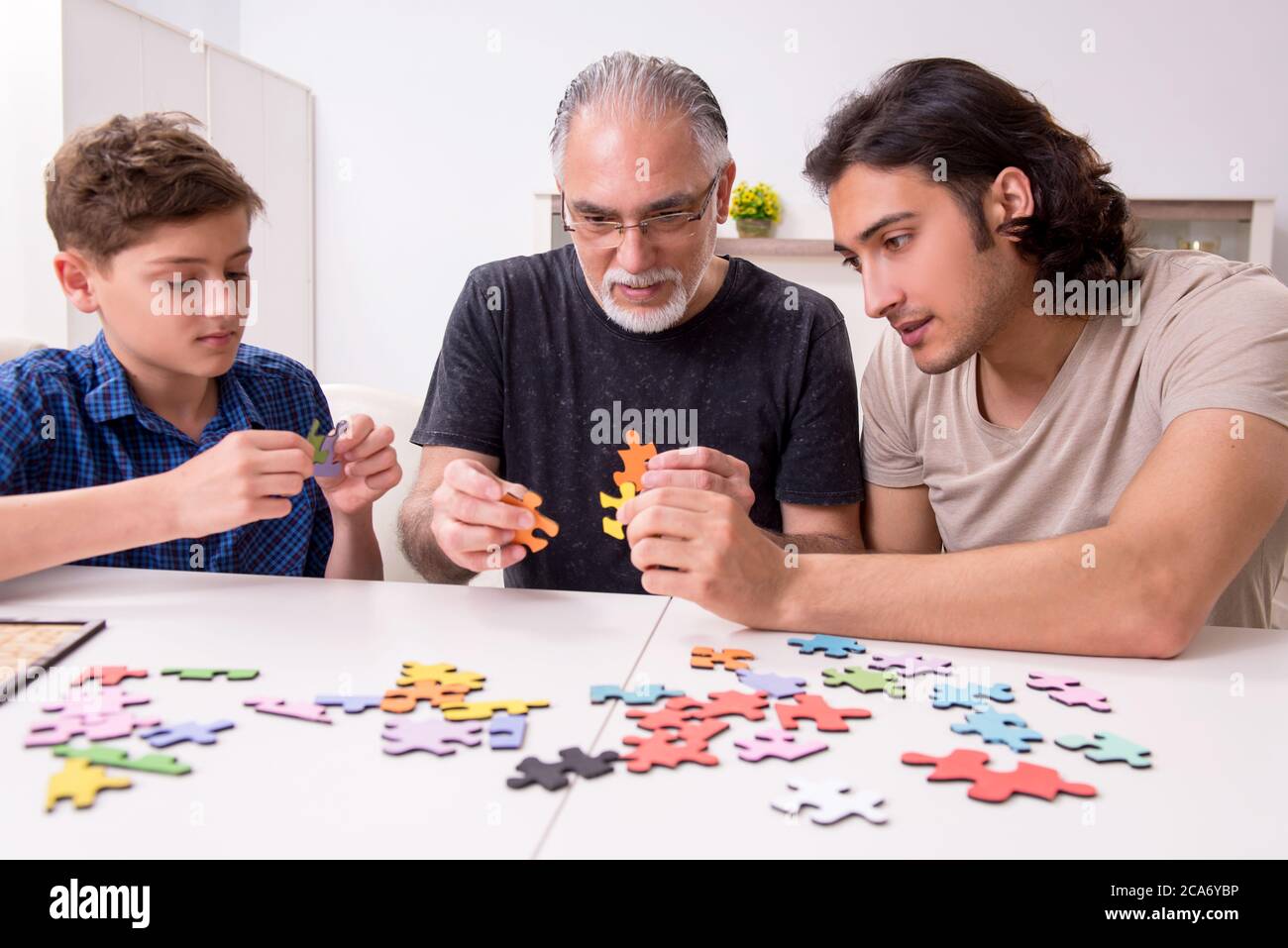 Three generations of family playing jigsaw puzzle Stock Photo - Alamy