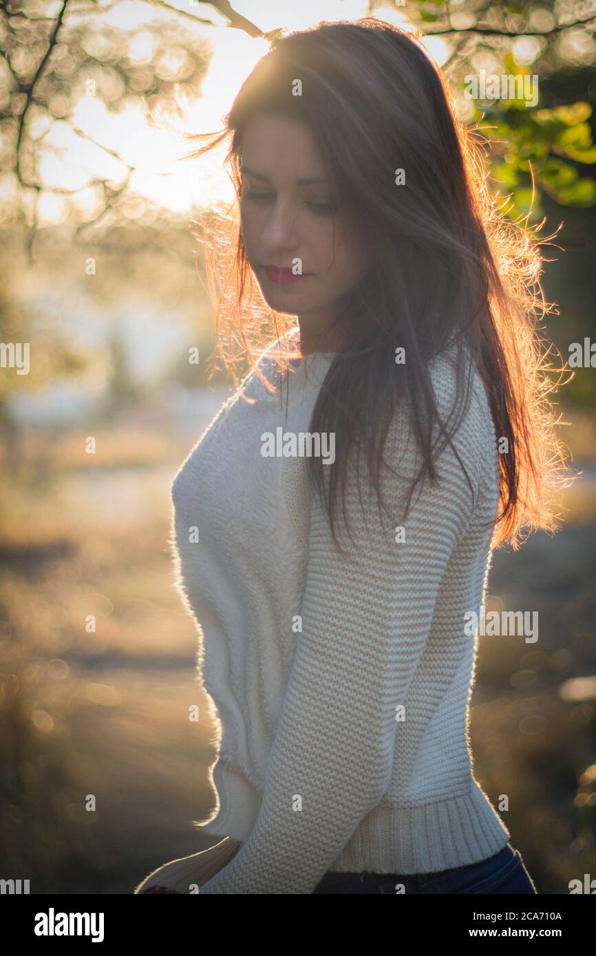 Pretty girl with long brown hair in a backlight at sunset Stock Photo ...