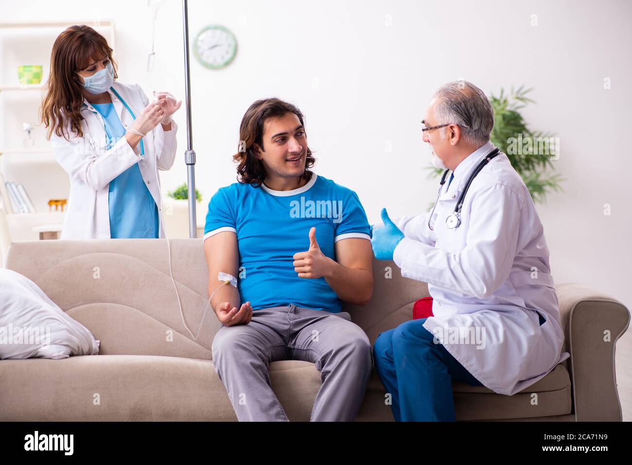 Two doctors visiting sick man at home Stock Photo - Alamy