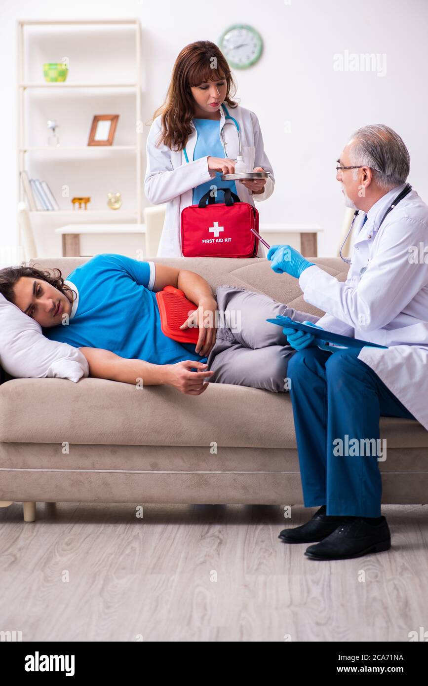 Two doctors visiting sick man at home Stock Photo - Alamy