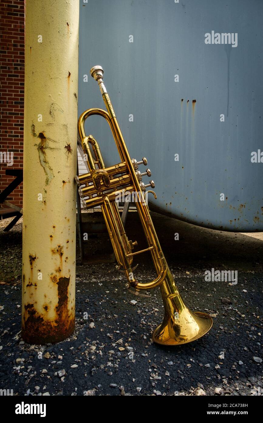 Abandoned old rusty Jazz trumpet leaning against yellow pillar on city ...