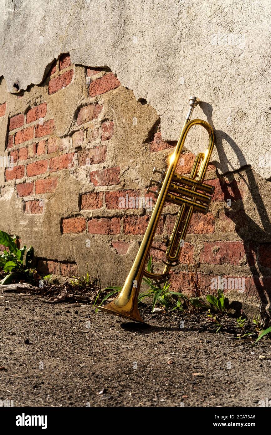 Old rusty Jazz instrument trumpet leaning against brick wall building ...