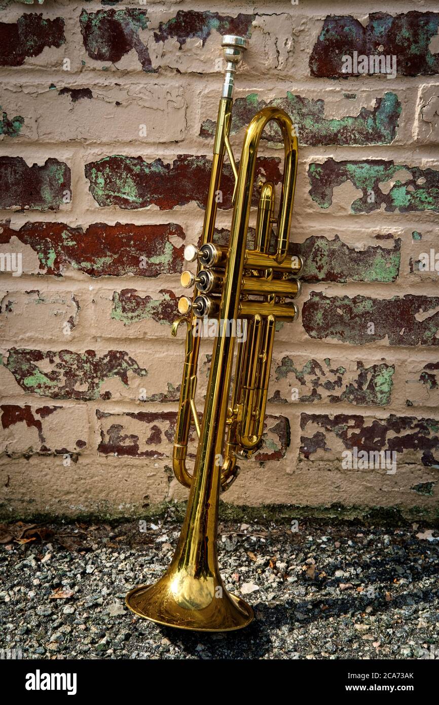 Old rusty Jazz instrument trumpet leaning against brick wall building ...