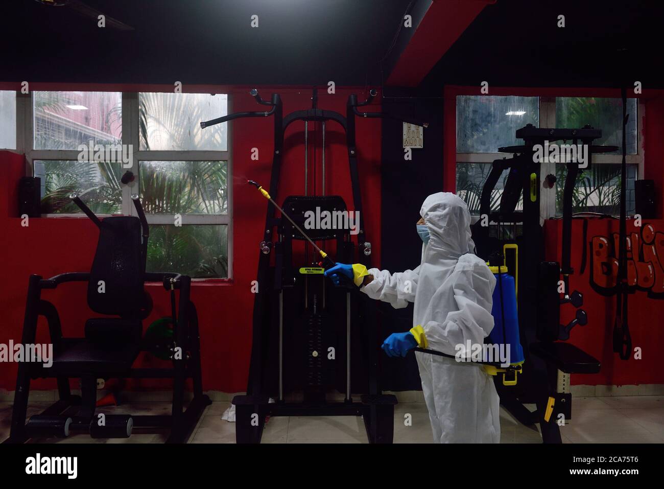A worker wearing a personal protective equipment suit (PPE) sanitizes ...