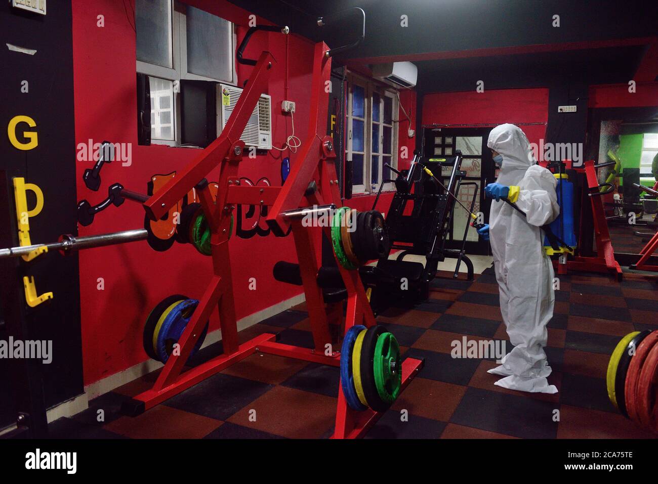 A worker wearing a personal protective equipment suit (PPE) sanitizes ...