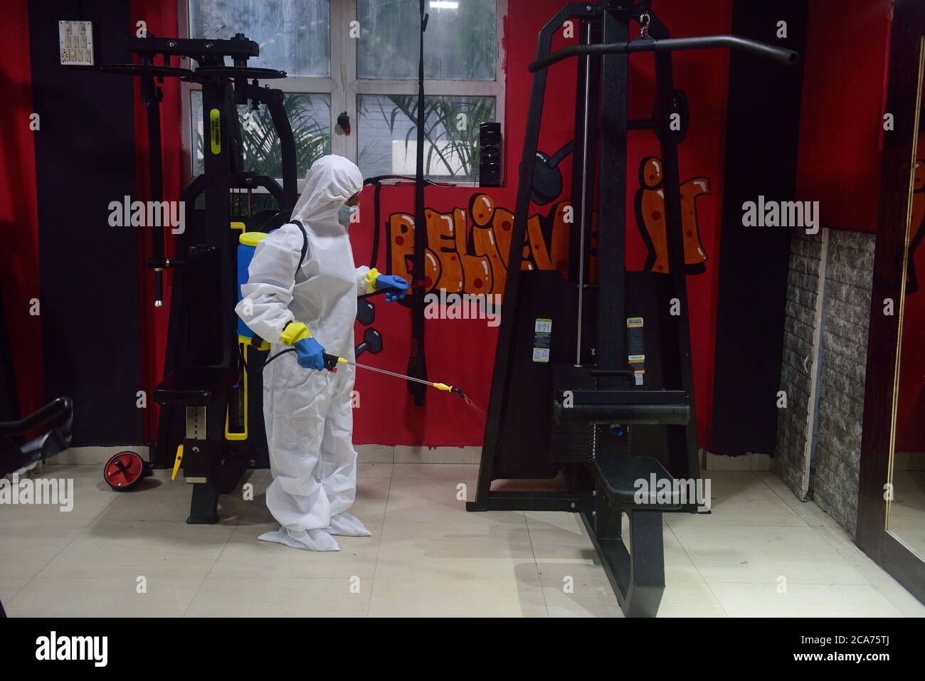 A worker wearing a personal protective equipment suit (PPE) sanitizes ...