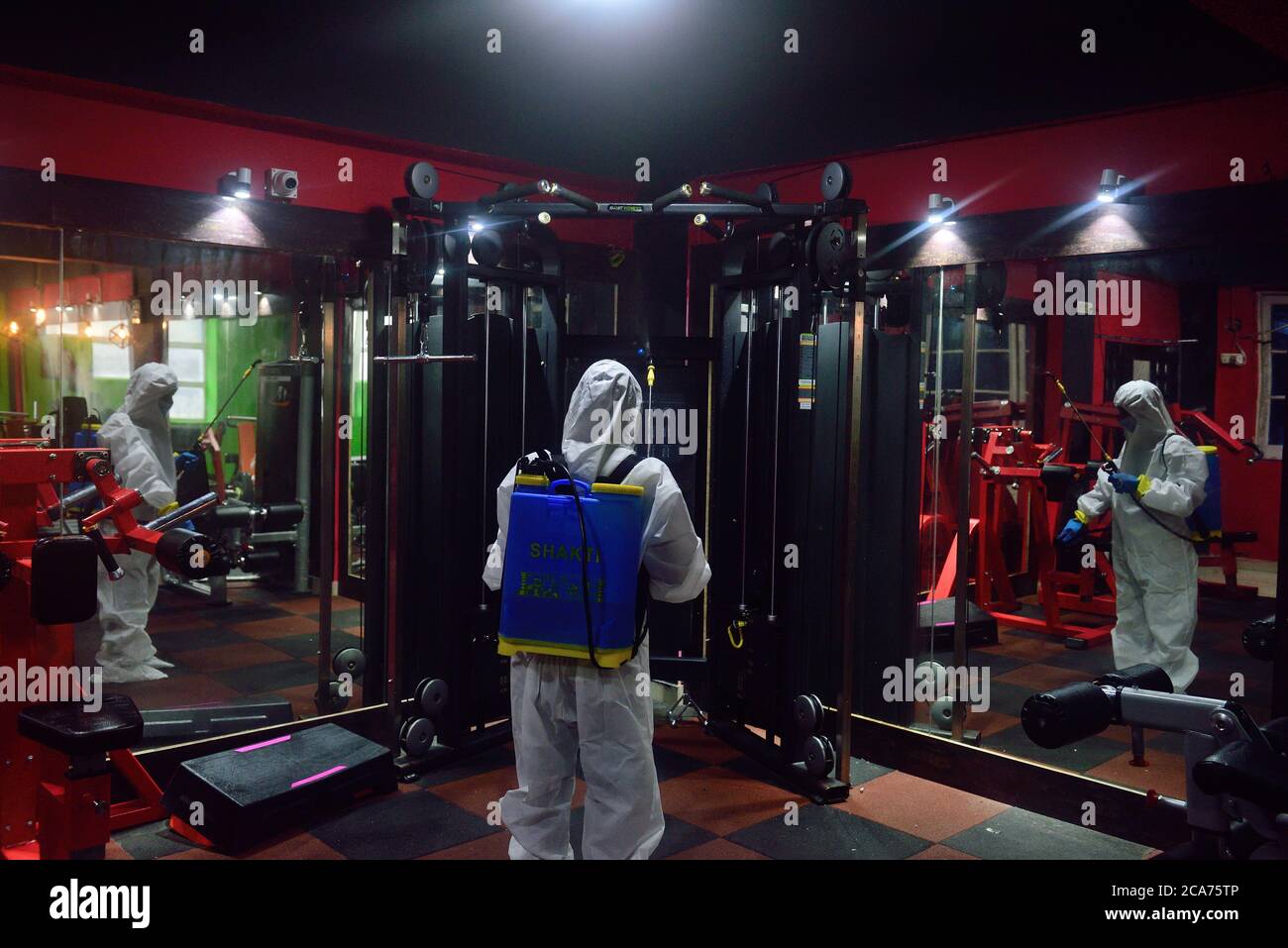A worker wearing a personal protective equipment suit (PPE) sanitizes ...