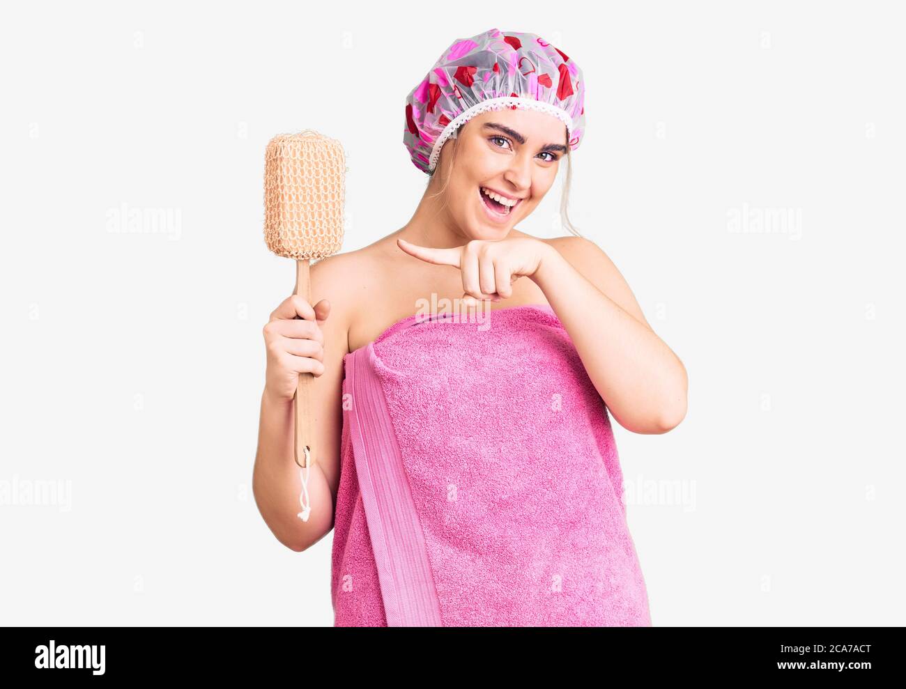 Young caucasian woman wearing shower cap and towel holding sponge ...
