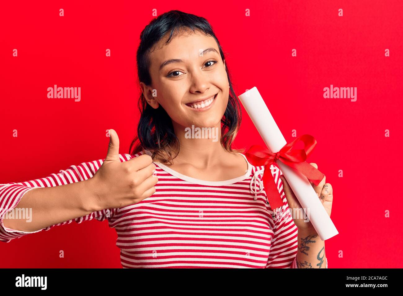 Young woman holding graduate degree diploma smiling happy and positive ...