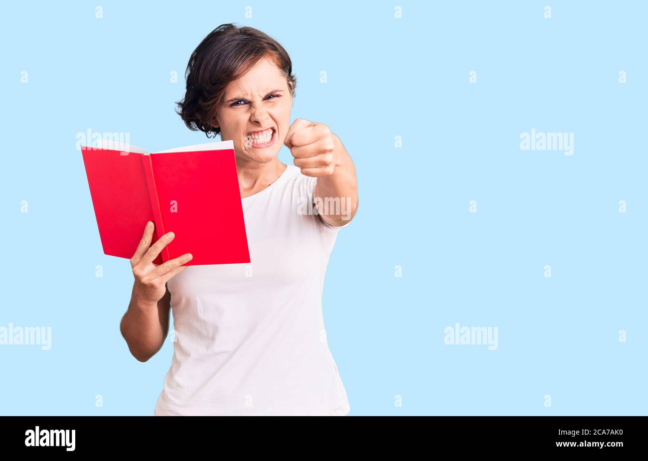 Beautiful young woman with short hair reading a book annoyed and ...