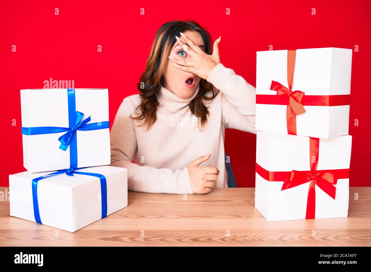 Young beautiful caucasian woman sitting on the table with presents ...