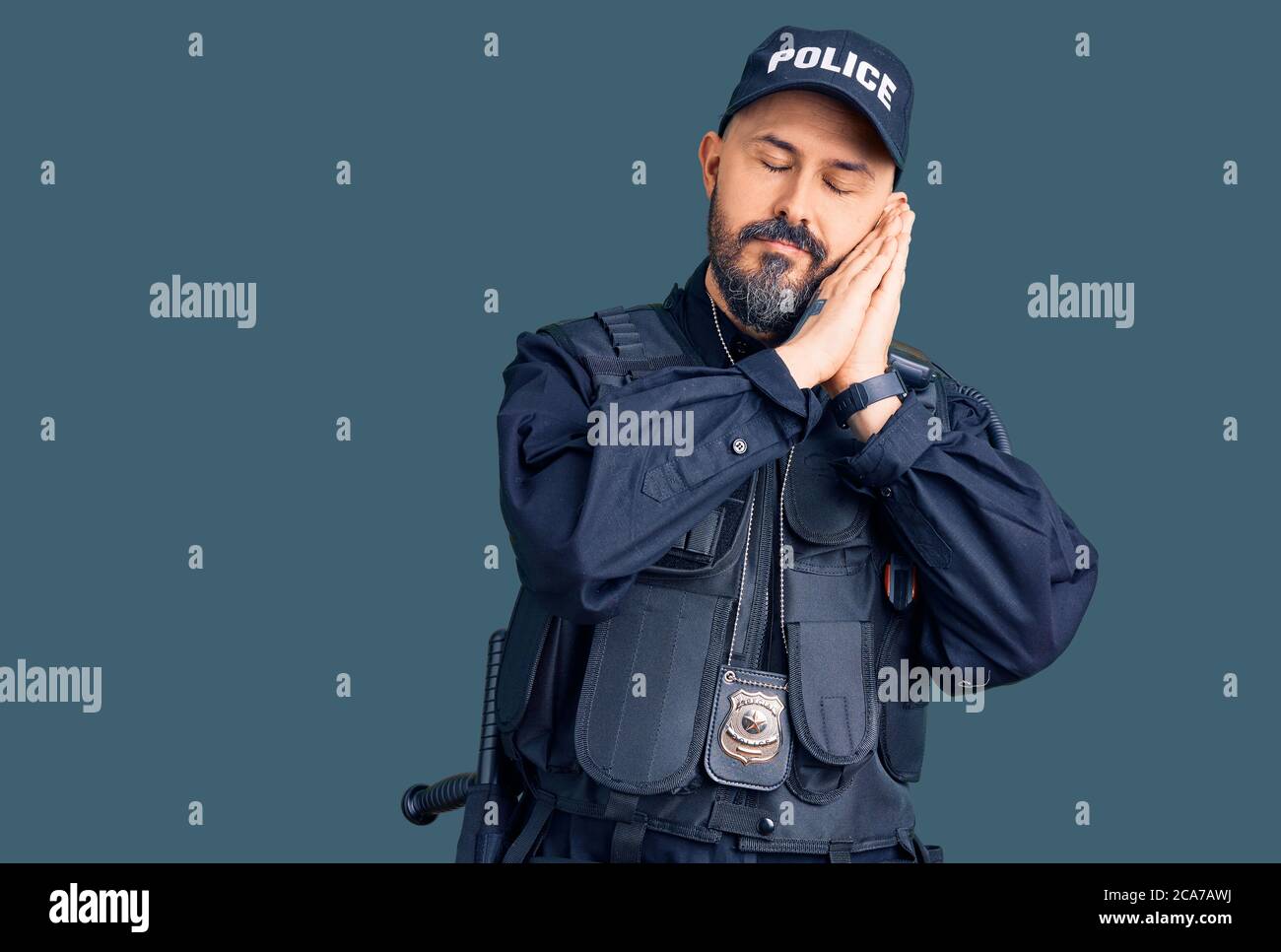 Young handsome man wearing police uniform sleeping tired dreaming and ...