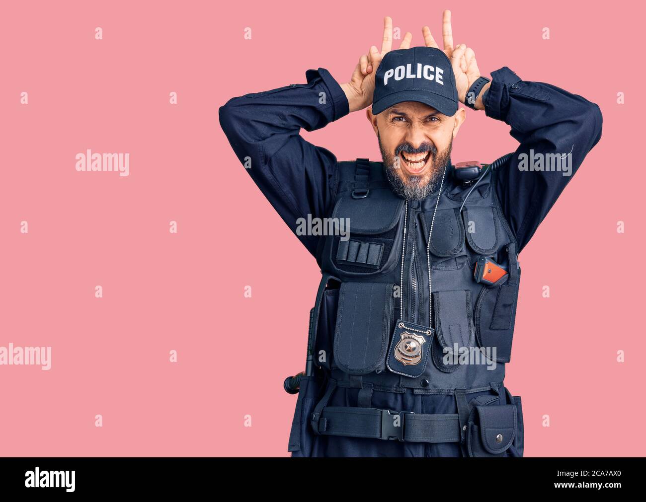 Young handsome man wearing police uniform posing funny and crazy with ...