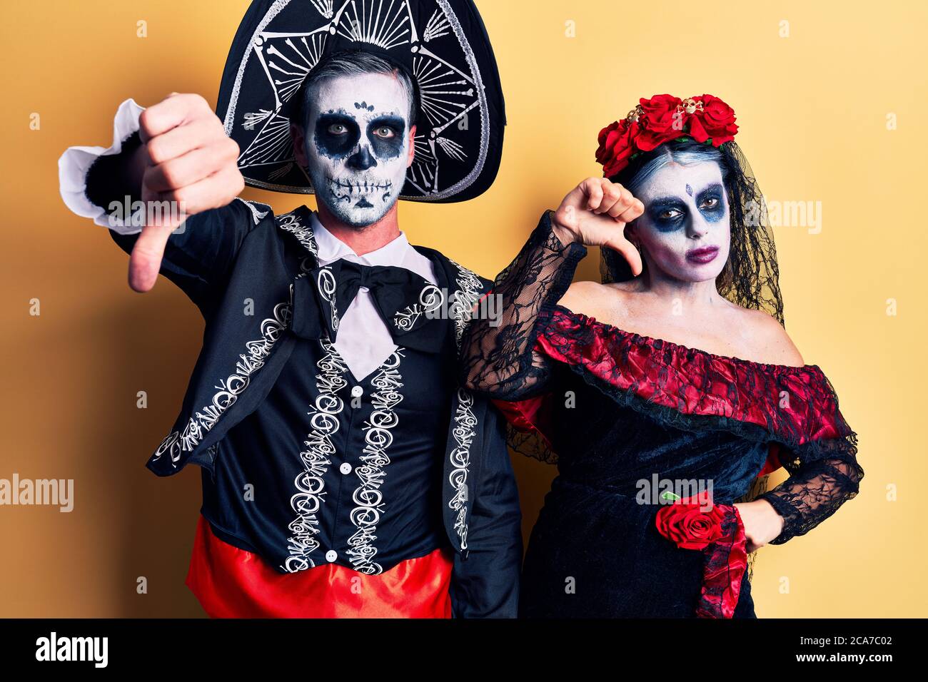 Young couple wearing mexican day of the dead costume over yellow ...