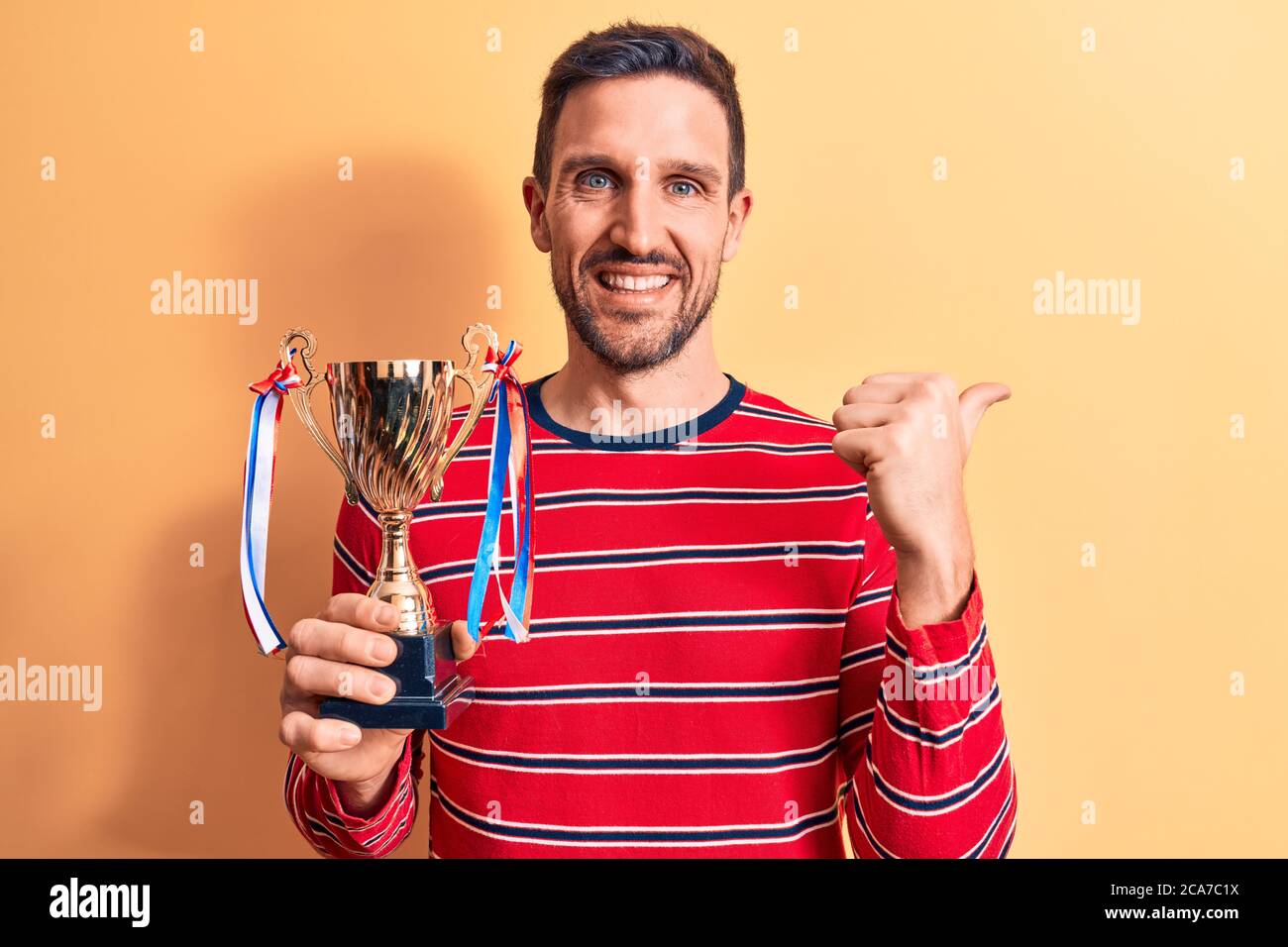 Young handsome successful man winning trophy standing over isolated ...