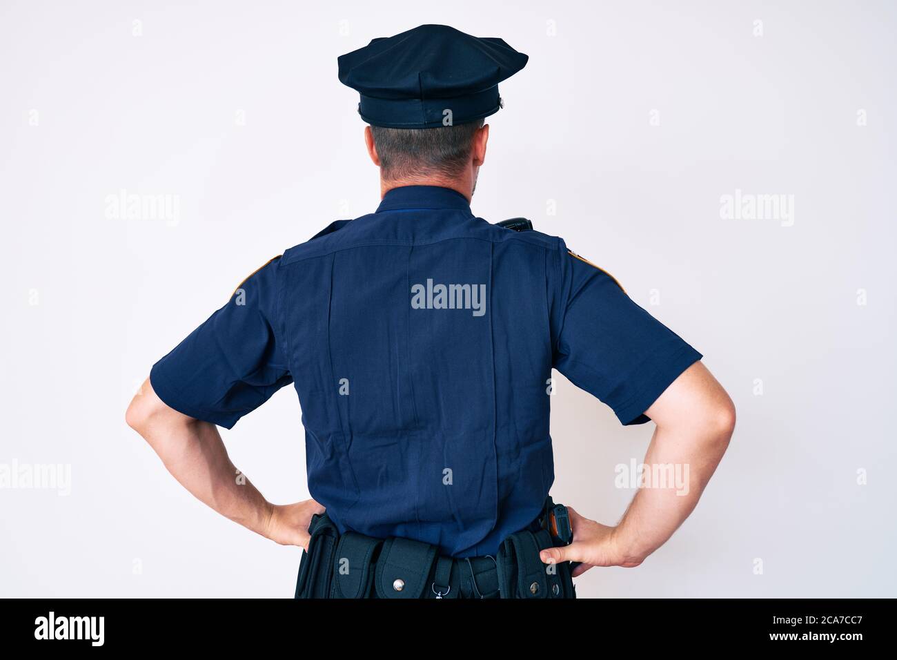 Young caucasian man wearing police uniform standing backwards looking ...