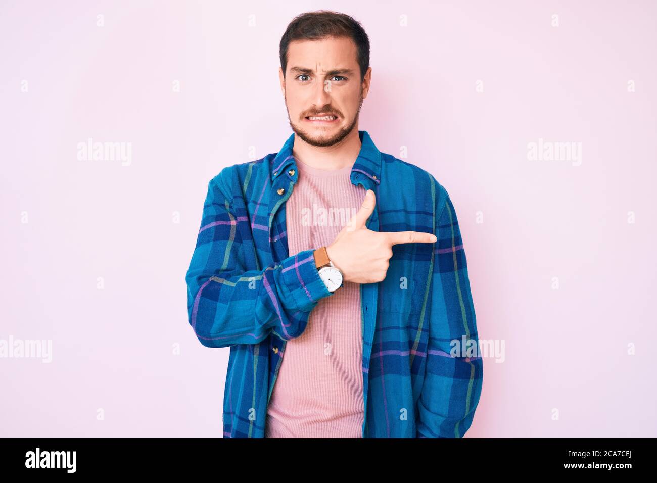 Young handsome man wearing casual clothes pointing aside worried and ...