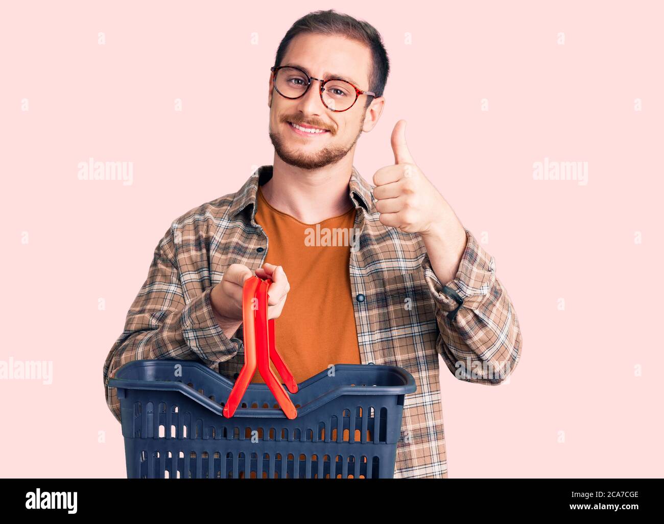 Young handsome caucasian man holding supermarket shopping basket ...
