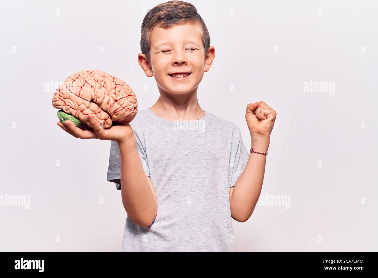 Cute blond kid holding brain screaming proud, celebrating victory and ...