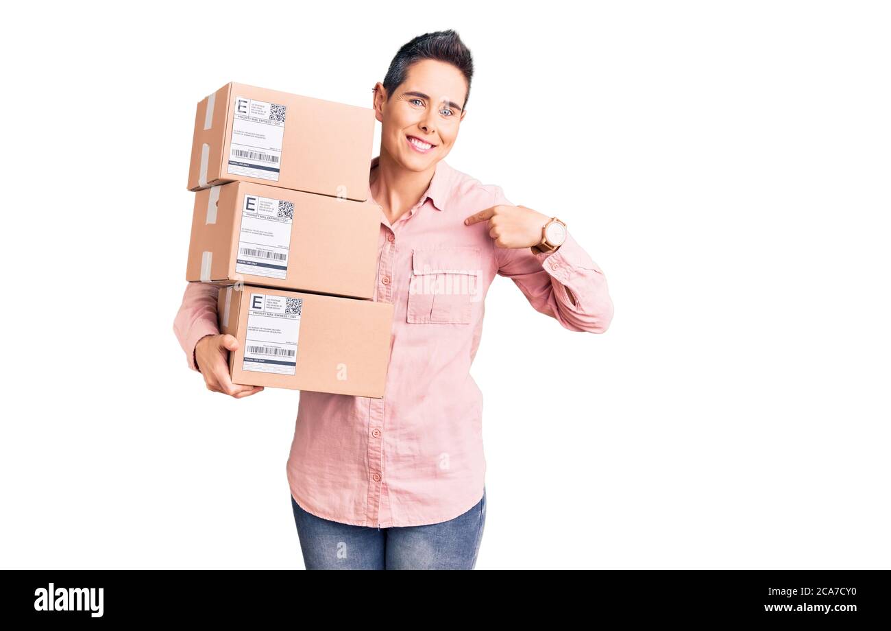 Young woman with short hair holding delivery package pointing finger to ...