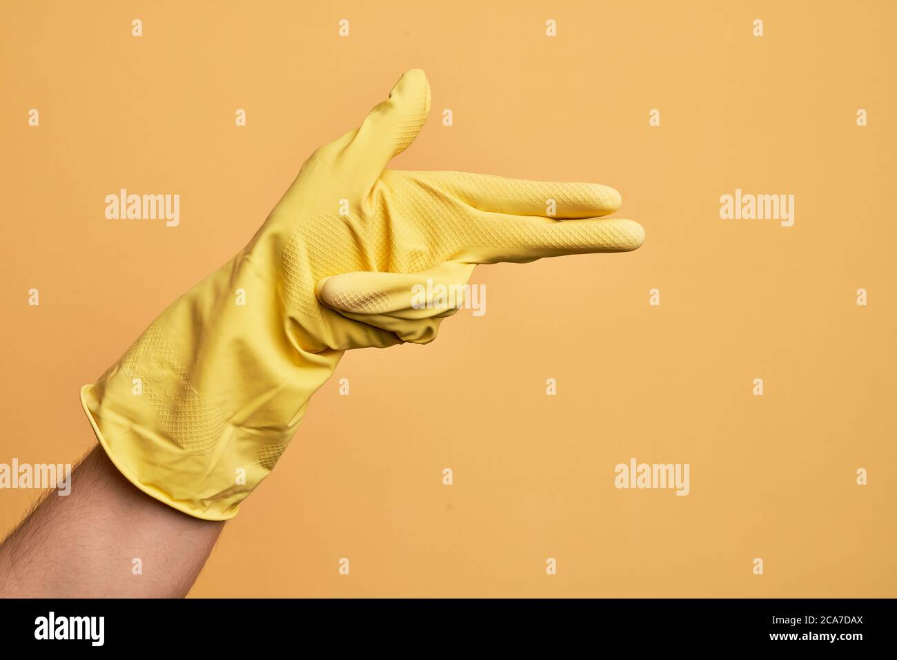 Hand of caucasian young man with cleaning glove over isolated yellow ...