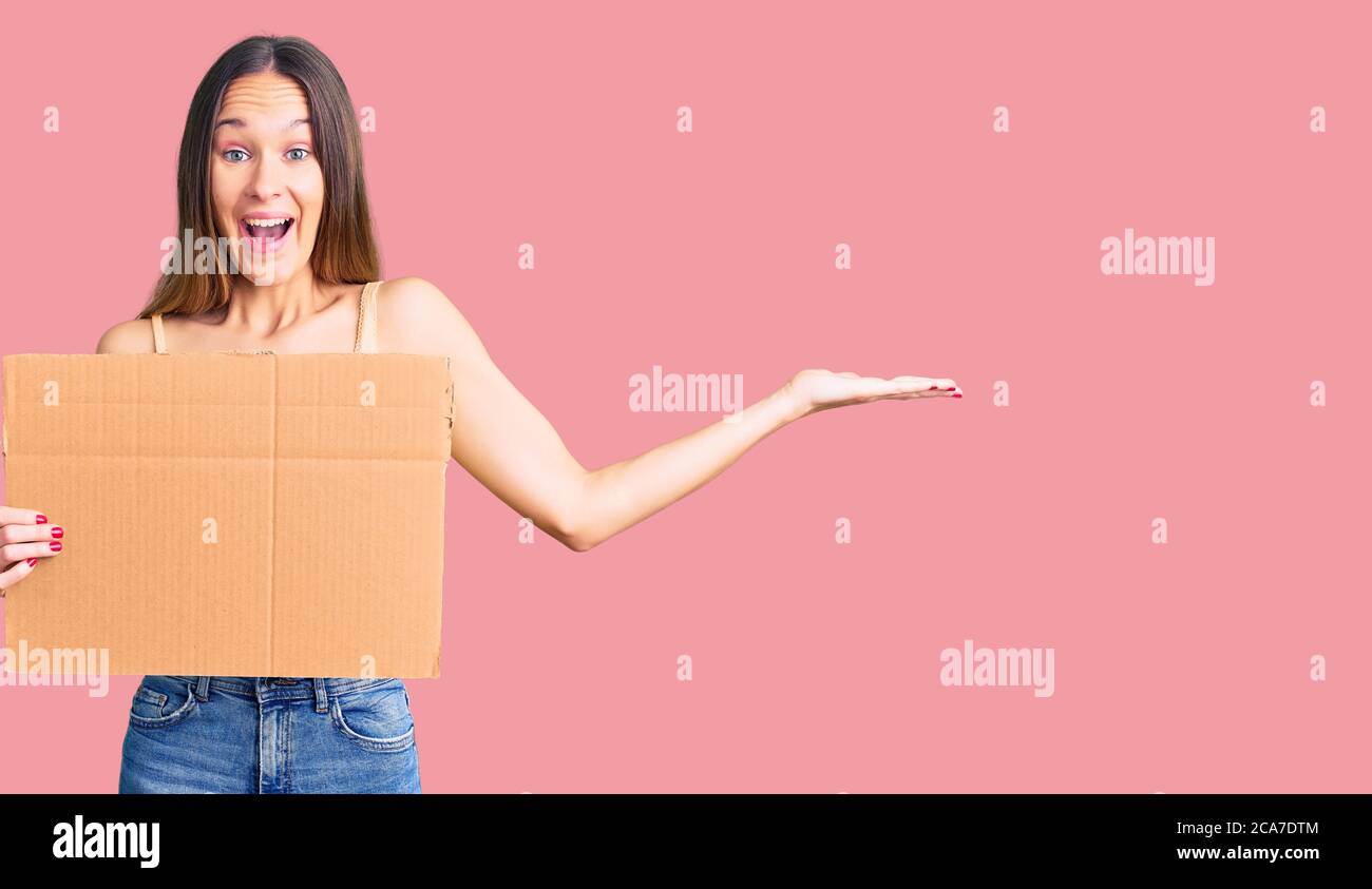 Beautiful brunette young woman holding cardboard banner with blank ...