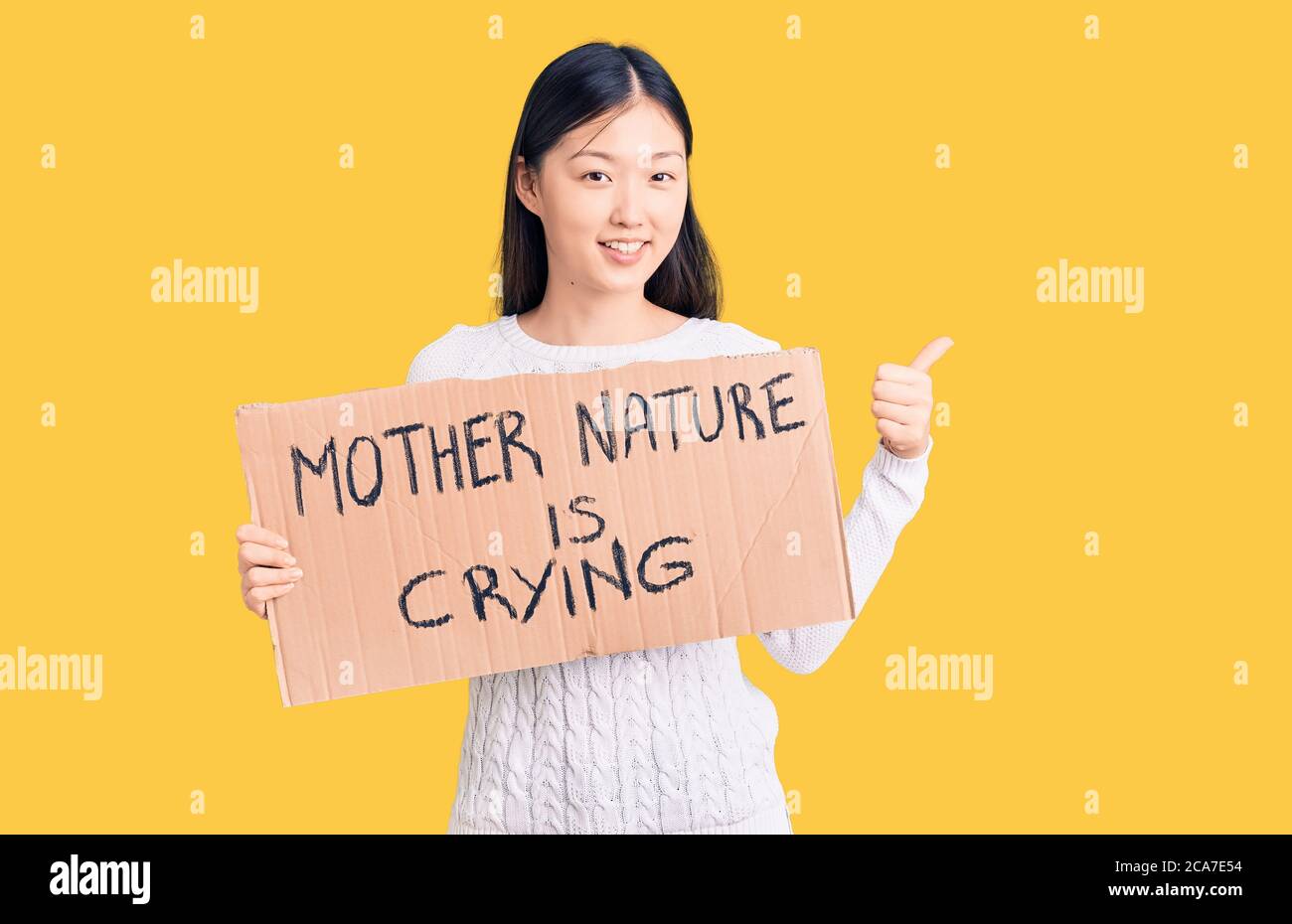 Young beautiful chinese woman holding mother nature is crying cardboard ...