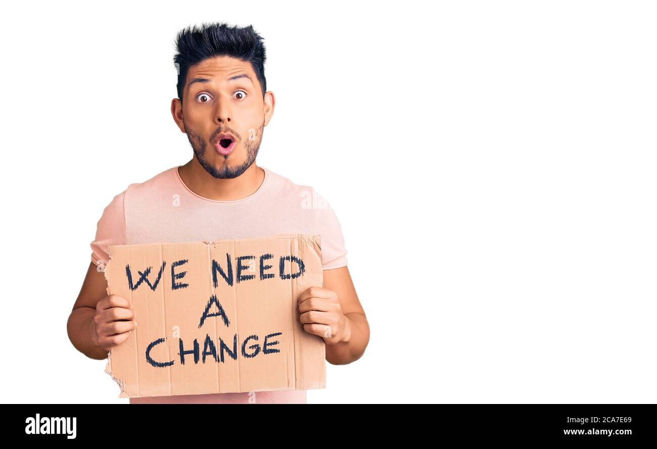 Handsome latin american young man holding we need a change banner ...