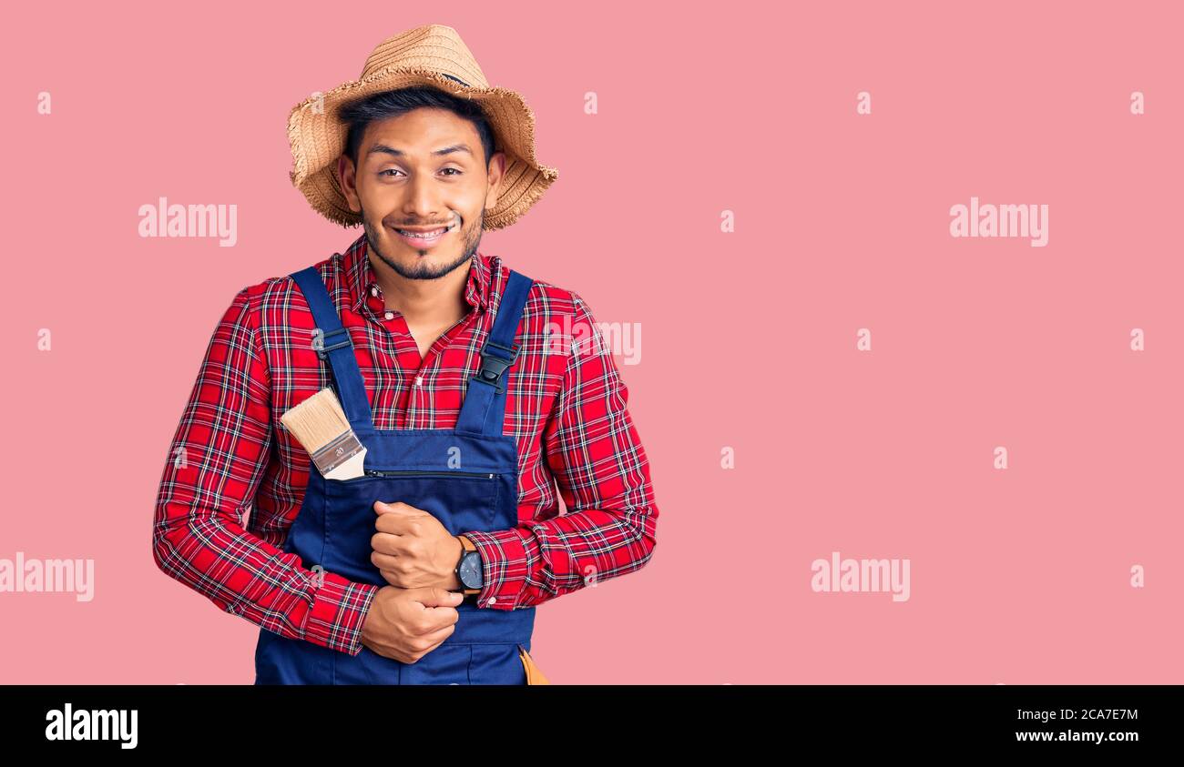 Handsome latin american young man weaing handyman uniform smiling and ...
