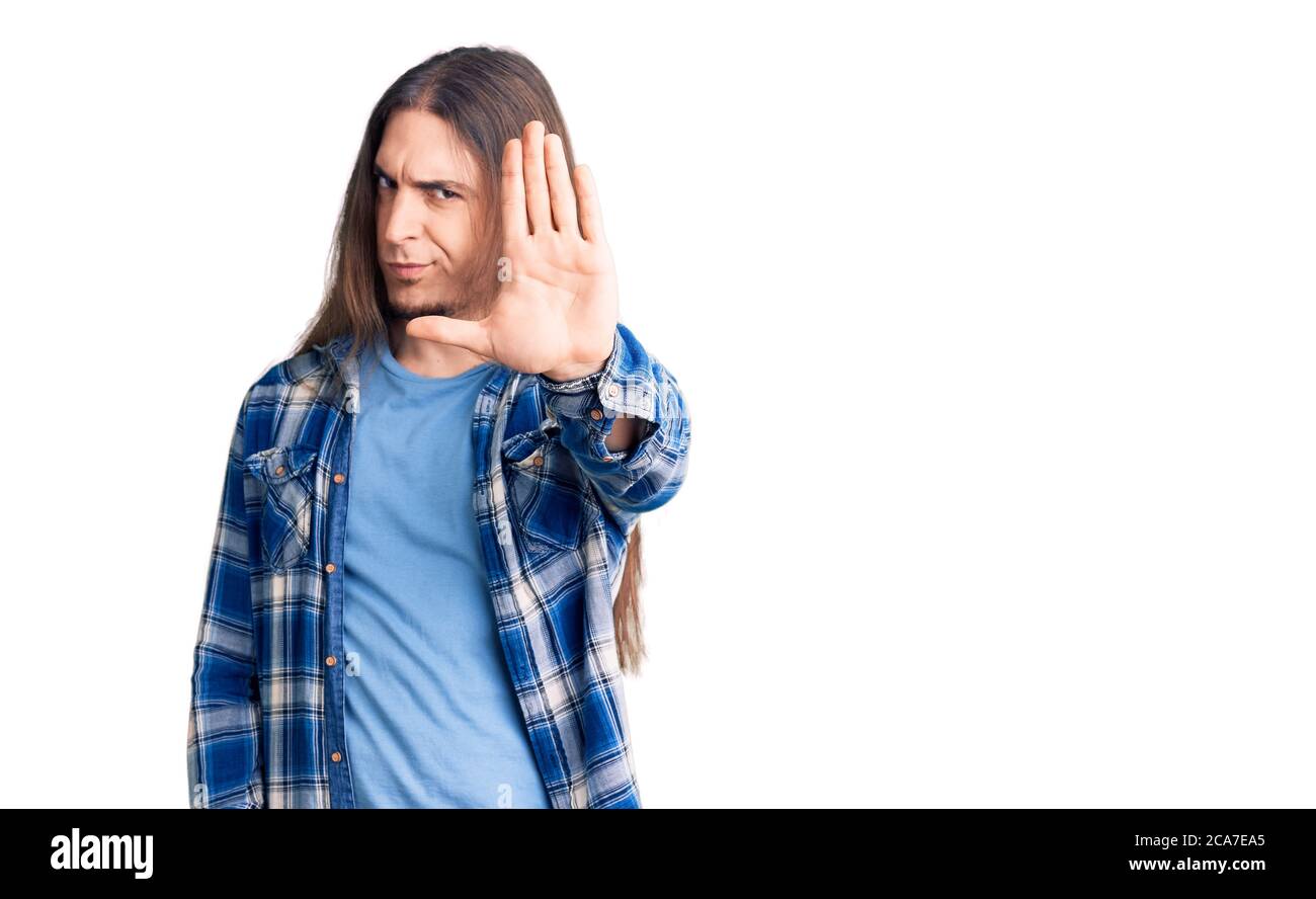 Young adult man with long hair wearing casual shirt doing stop sing ...