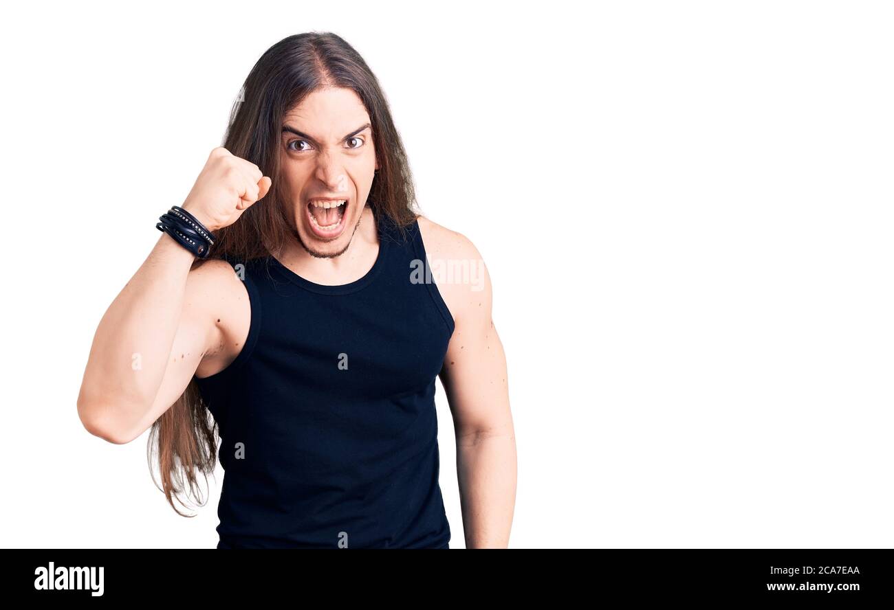 Young adult man with long hair wearing goth style with black clothes ...