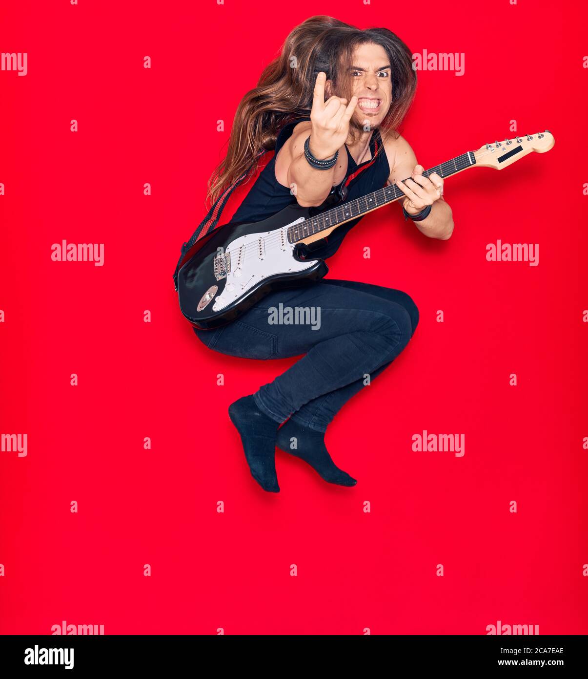 Young handsome man with long hair and aggressive expression playing ...