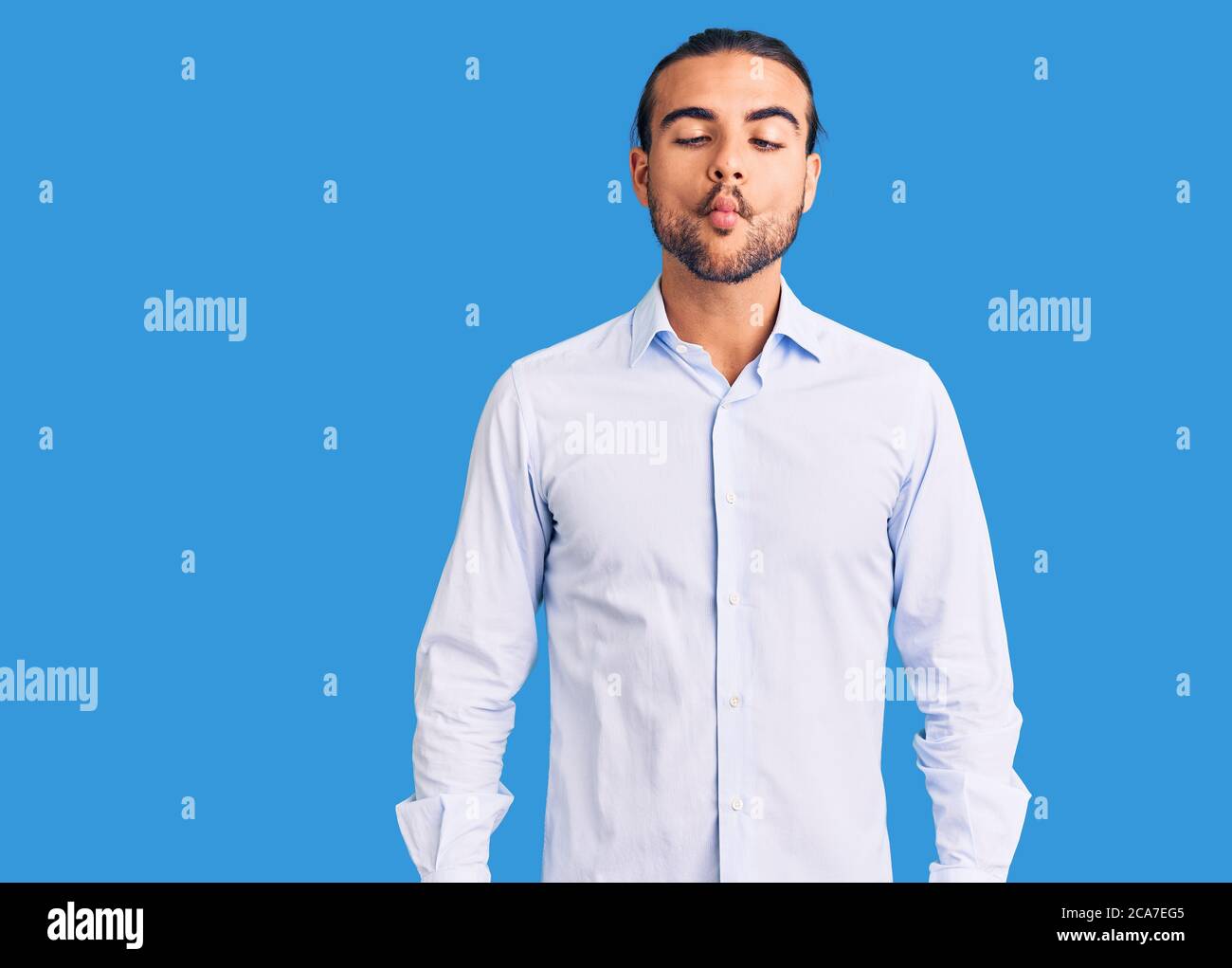 Young handsome man wearing business clothes making fish face with lips ...
