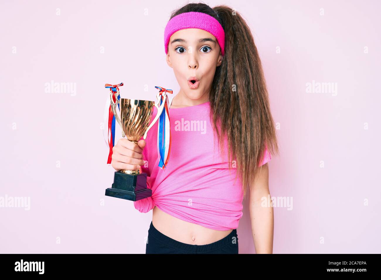 Cute hispanic child girl wearing sportswear holding winner trophy ...