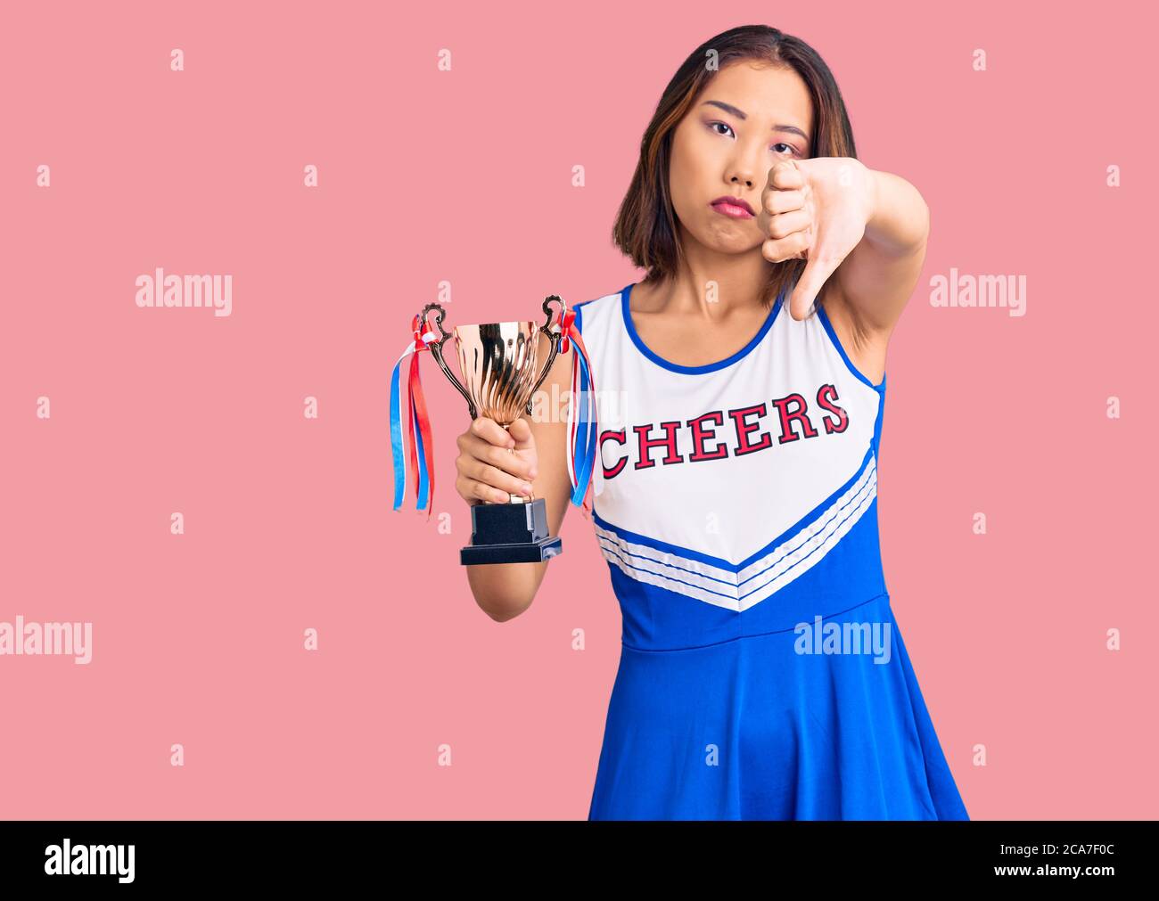 Youn beautiful asian girl wearing cheerleader uniform holding champion ...
