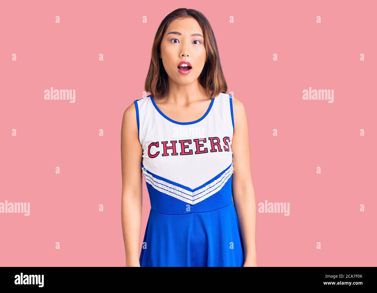 Young beautiful chinese girl wearing cheerleader uniform afraid and ...