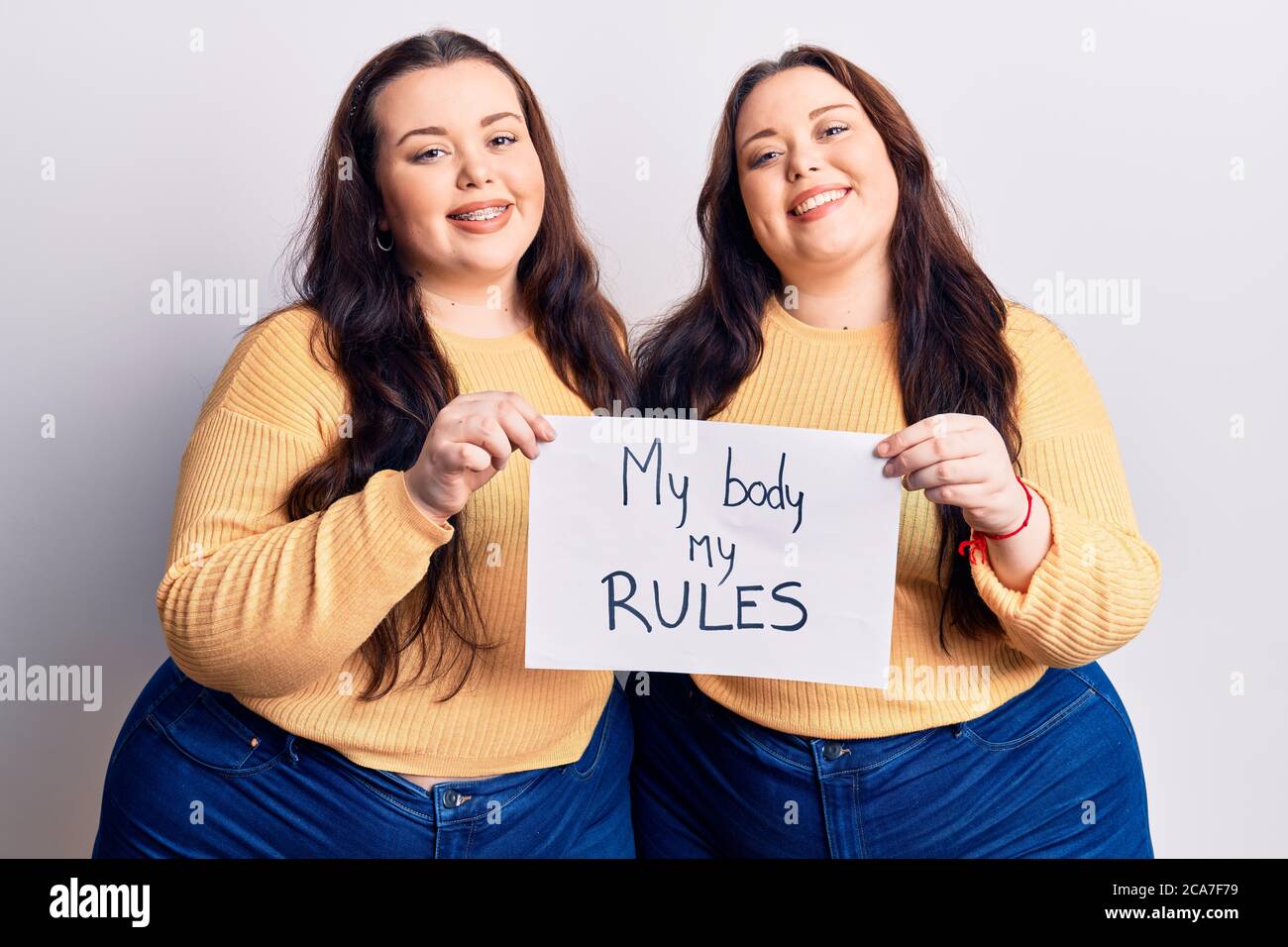 Young plus size twins holding my body my rules banner looking positive ...