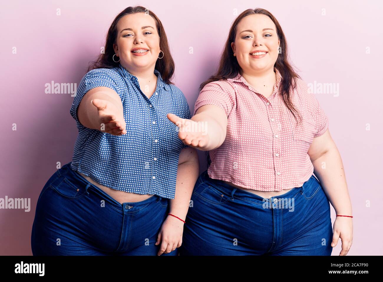 Young plus size twins wearing casual clothes smiling friendly offering ...