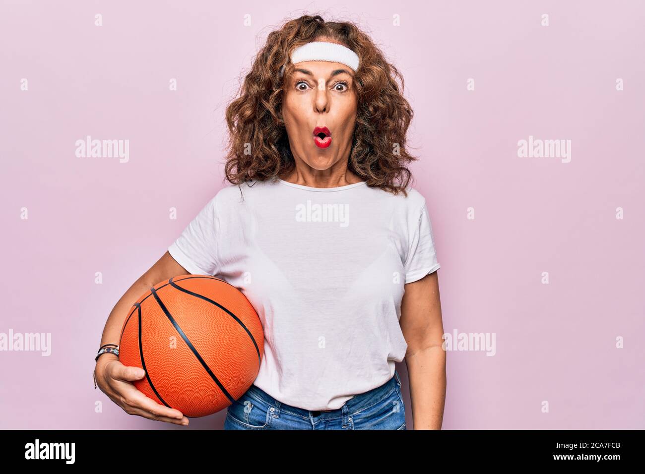 Middle age brunette basketball player woman holding game ball over ...