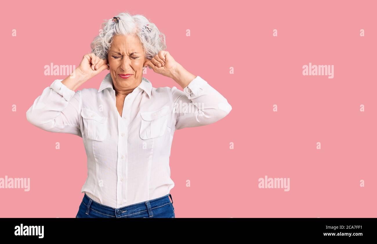 Senior grey-haired woman wearing casual clothes covering ears with ...