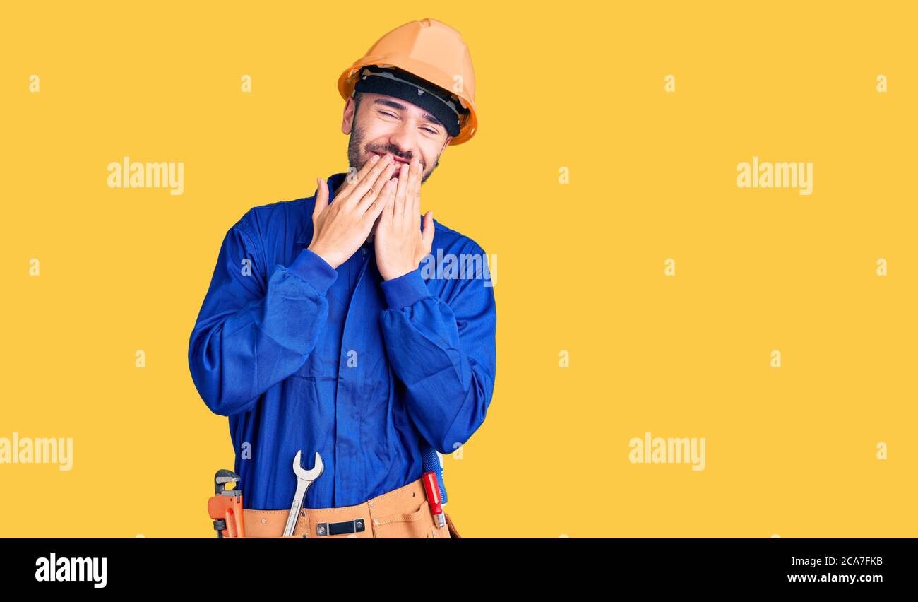 Young hispanic man wearing worker uniform laughing and embarrassed ...