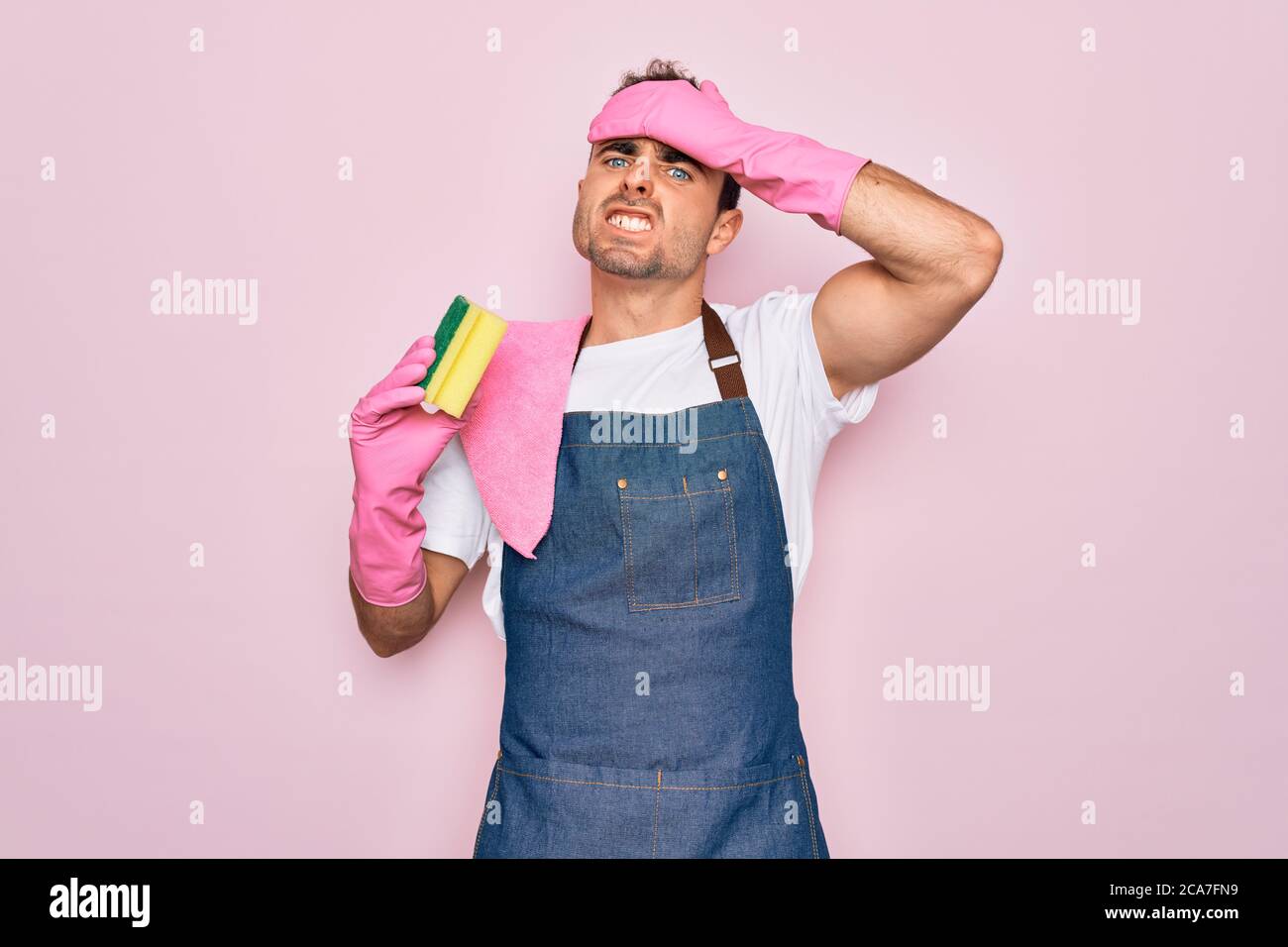 Young cleaner man with blue eyes cleaning wearing apron and gloves ...