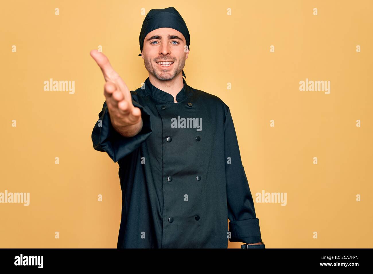 Young handsome cooker man with blue eyes wearing uniform and hat over ...