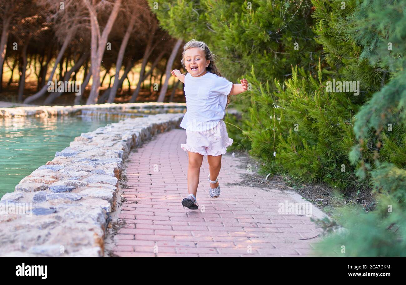 Adorable blonde child smiling happy. Running with smile on face around ...