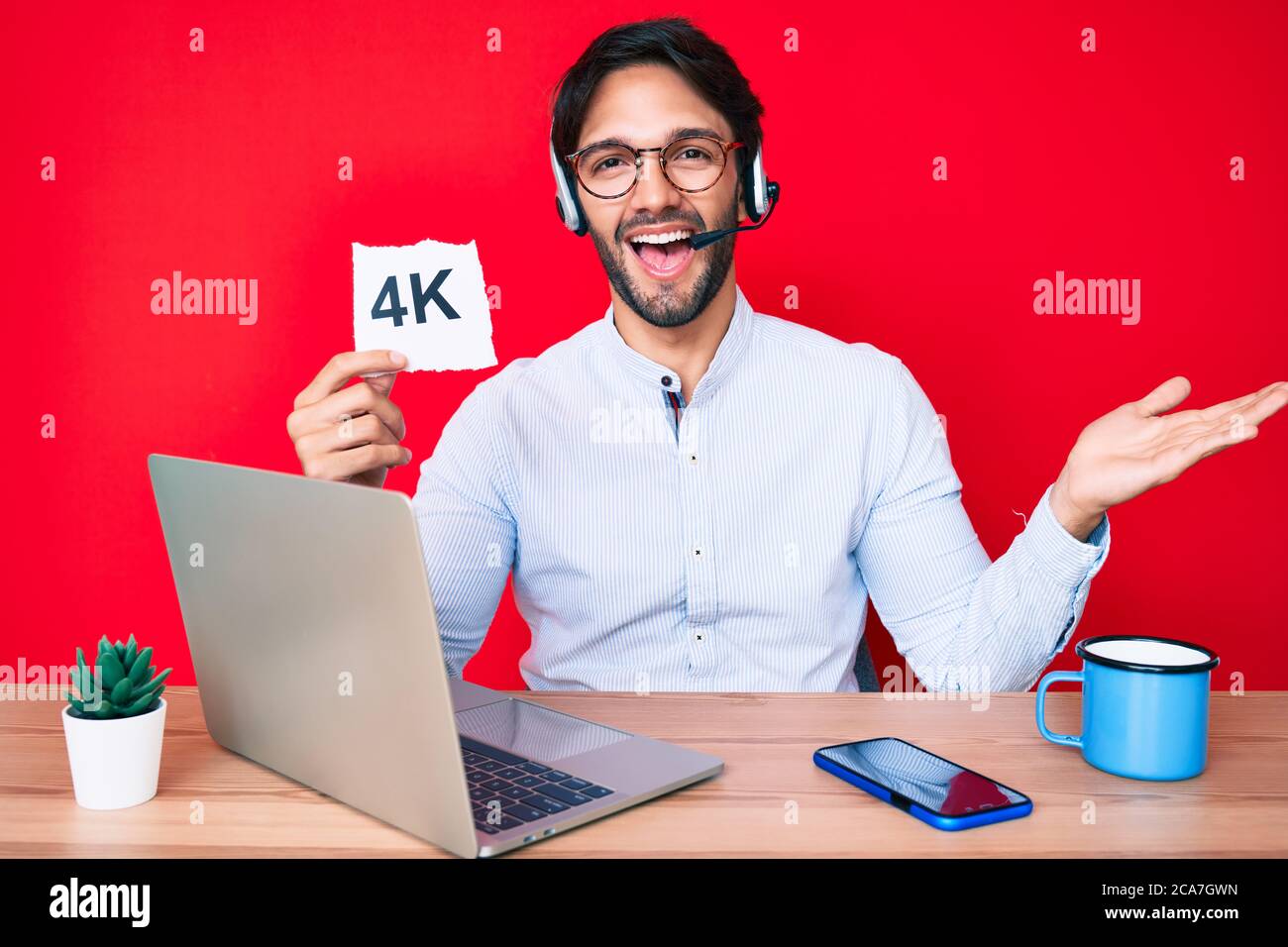 Handsome hispanic man working at the office holding 4k banner ...