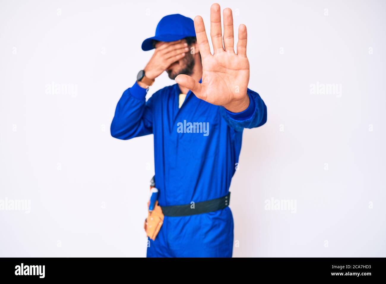 Handsome young man with curly hair and bear weaing handyman uniform ...