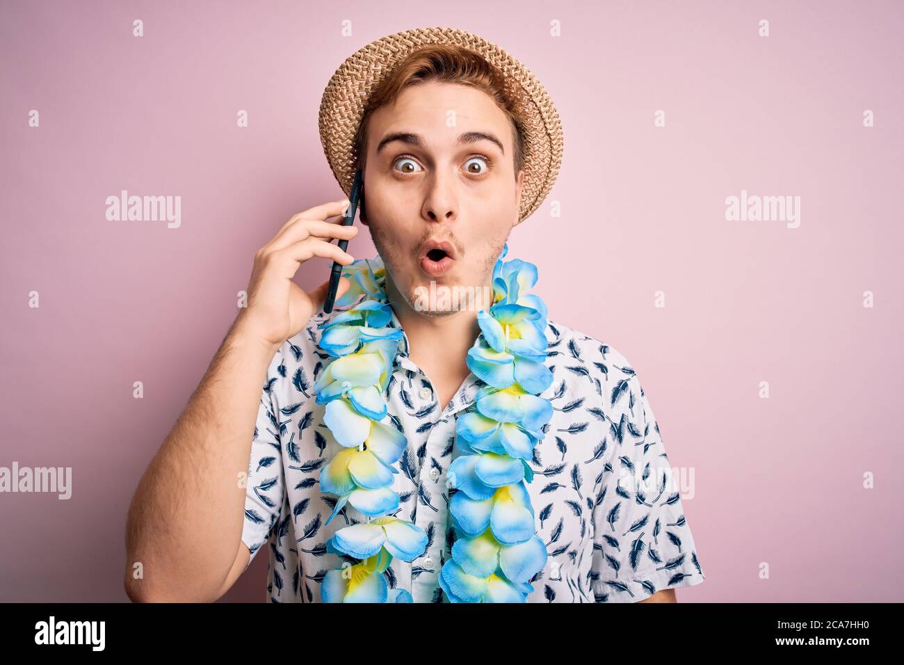 Young man on vacation wearing hat and hawaiian lei having conversation ...