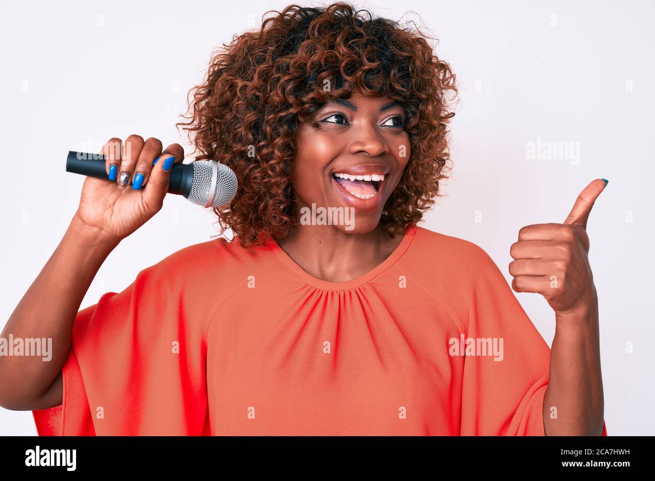 Young african american woman singing song using microphone pointing ...