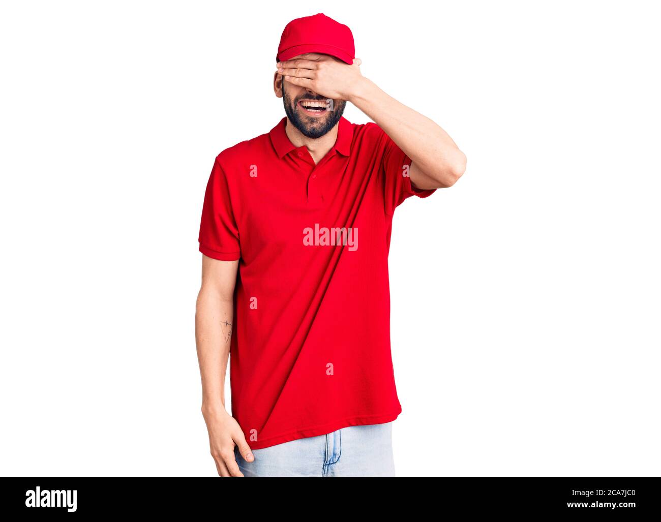 Young handsome man with beard wearing delivery uniform smiling and ...